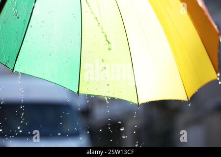 Open bright umbrella under pouring rain outdoors, closeup. Space for ...