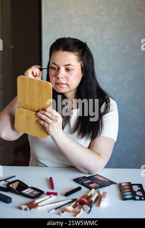young woman applying lipstick while doing makeup on sofa at home Stock ...