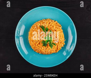 Pilaf on the brown plate on a wooden background. Top view. Copy space ...