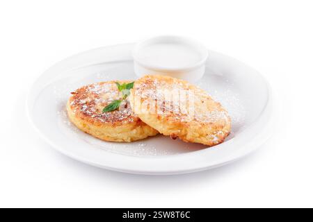Two homemade cheese pancakes on ceramic saucer with white napkin, metal ...