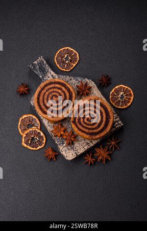 Freshly baked cinnamon roll with spices and cocoa filling on a black ...