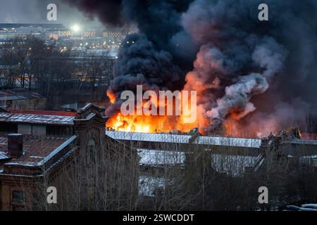 Burning factory building with orange flames, sparks and thick toxic ...