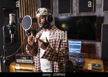 Young African performer recording his new track in recording studio ...