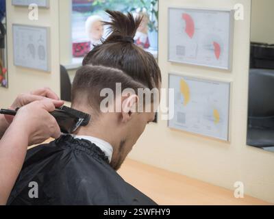 Barber works with a beard clipper. Hipster client getting haircut Stock ...