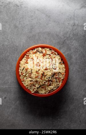 Earthenware bowl full of long, red, wild rice on a kitchen countertop ...