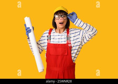 Funny young female decorator with house plan on orange background. Fool ...