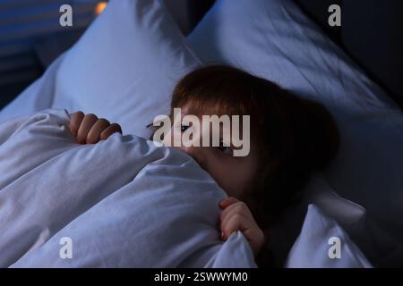 Scared boy hiding under duvet in bed at night Stock Photo - Alamy