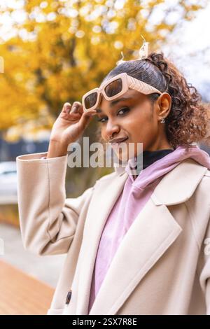 Afro Woman holding her sunglasses and looking at the camera while ...