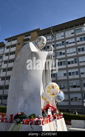 People pray near the statue of John Paul II outside the Gemelli ...