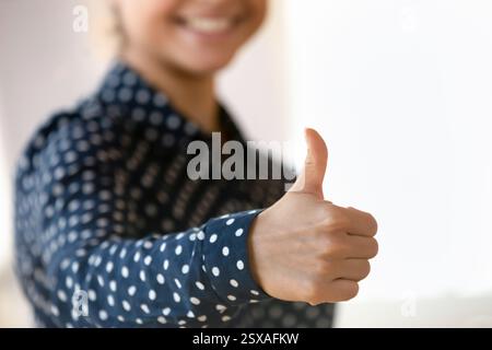cropped view of smiling woman showing thumb up while standing near bowl ...