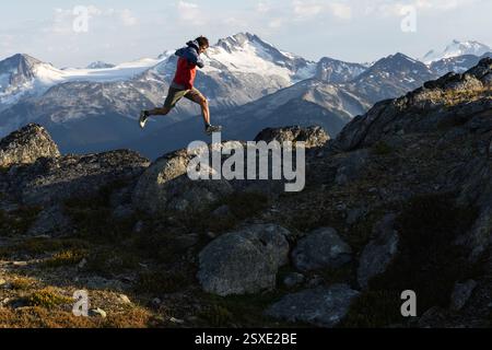 Trail runner running over rugged terrain with glaciers and mountains ...