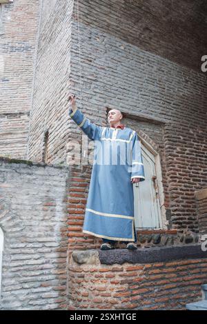 A bell ringer rings large church bells under the open sky. A ...