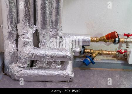 Silver aluminum foil insulation pipe wrapping duct work in dark attic ...
