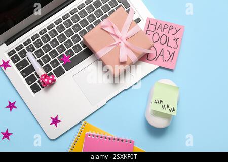Laptop, gift box, notebooks and sticky notes on blue background. April ...