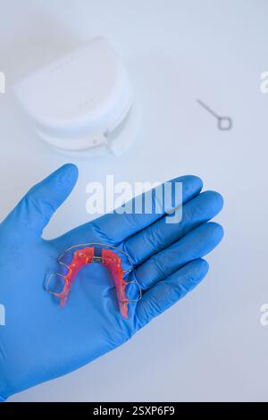 A dentist wearing gloves holds a palatal expander, an orthodontic ...