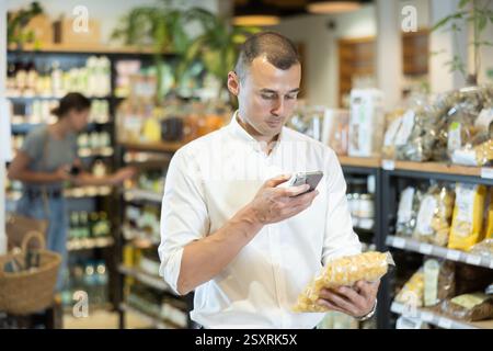 Young man purchaser scanning QR code of pasta in grocery store Stock ...