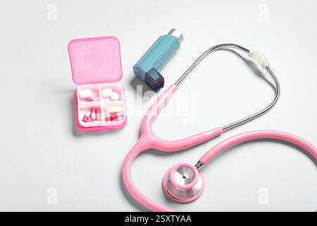 Composition with asthma inhaler, stethoscope and box of pills on lilac ...