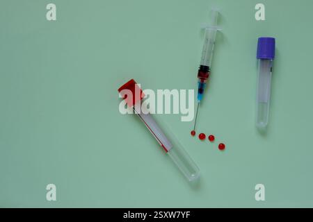 Syringe, and test tube with red plug and red blood. Blood drops on the ...