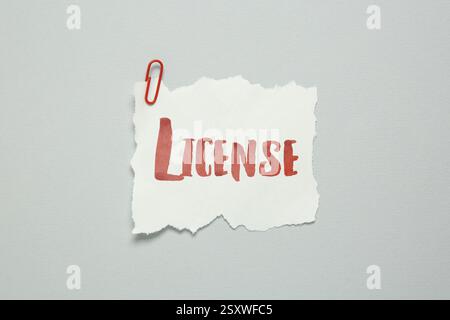Piece of paper with word License and paperclip on white background, top ...