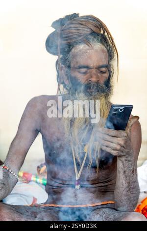spiritual hindu naga saint watching mobile phone at mahakumbh mela ...