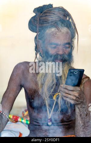 spiritual hindu naga saint watching mobile phone at mahakumbh mela ...