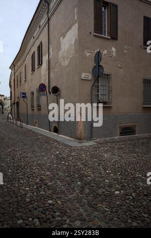 Crossing between cobbled streets partly in the shade at the corner of a ...