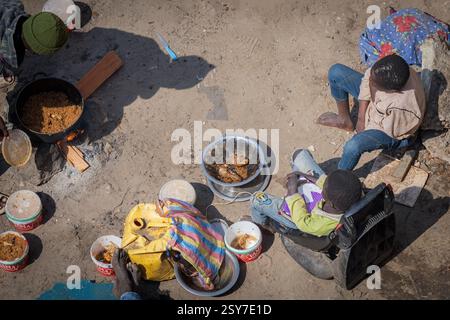 Top view of the poor family cooking food in the house yard on the fire ...