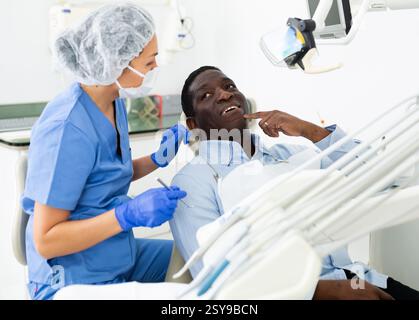 Patient pointing at tooth with problem during consultation in dental ...