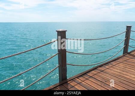Wooden pier with posts and ropes with sparkling sea water. Wooden pier ...