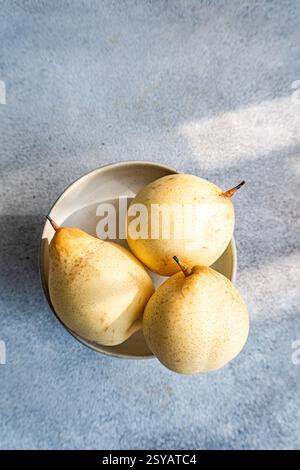 Three Chinese white pears in a bowl are placed on a textured surface ...