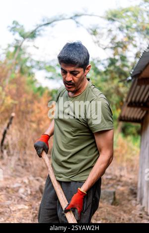 Man digging soil with a hoe in a garden Stock Photo - Alamy