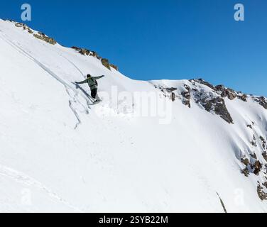 A snowboarder skillfully descends a steep, snowy mountain slope ...