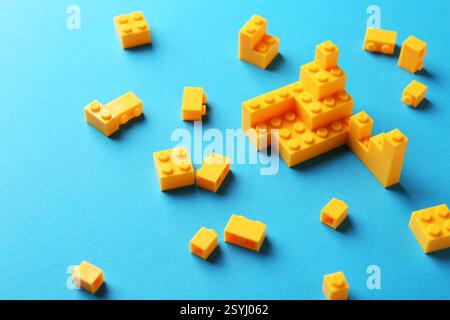 Constructor toy. Many yellow building blocks on light blue background ...