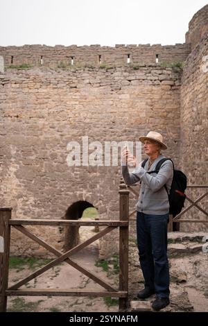 Elderly man in hat visiting medieval fortress taking photo for memory ...