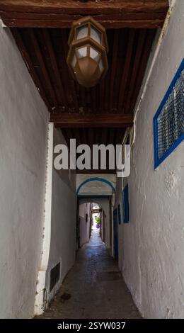 narrow, dimly lit passageway with whitewashed walls, a wooden beamed ...