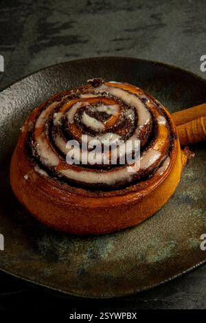 Freshly baked cinnamon roll with spices and cocoa filling on a black ...