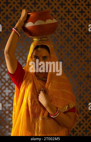Portrait of a happy Rajasthani woman carrying clay pot on her head ...