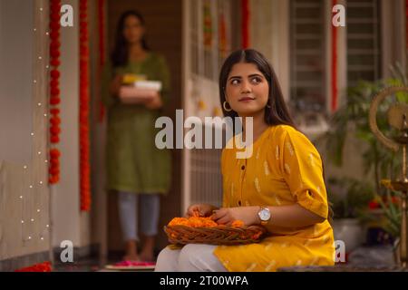 Young woman decorating house with flower on the occasion of Diwali ...