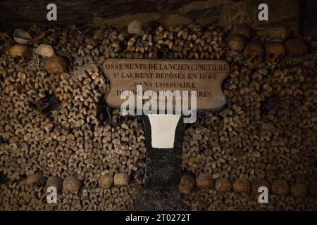 In the Paris Catacombs, a long underground path with structures formed ...