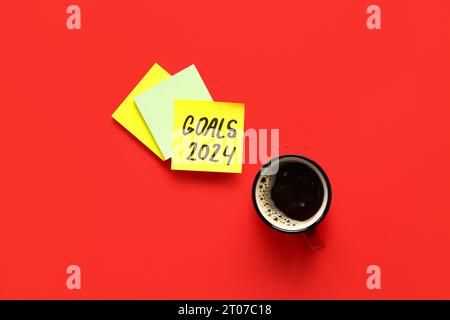 Sticky notes with goals for 2024 and cup of coffee on red background ...