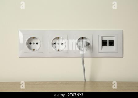 Many power sockets with plug, ethernet and TV coax plates on white wall ...