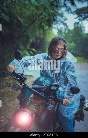 pretty woman wearing plastic rain clothes holding safety helmet ...