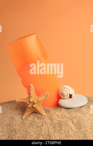Sand with bottle of sunscreen, starfish, stone and seashell against ...