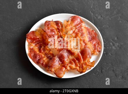 Roasted bacon on plate over black stone background. Close up view Stock ...