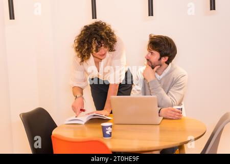 Female boss giving directions to worker at table in office Stock Photo ...
