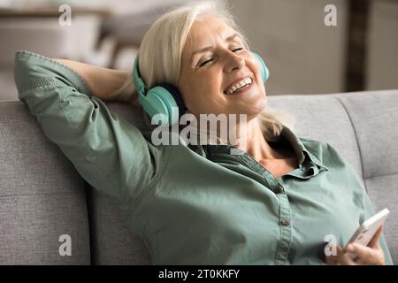 Middle age blonde woman singing song using microphone covering mouth ...