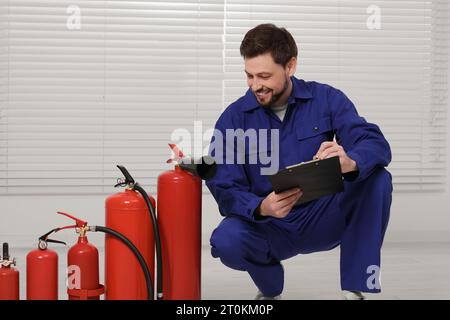 Man with clipboard checking fire extinguishers indoors Stock Photo - Alamy