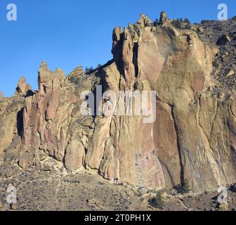 Rock climbers scaling a rugged cliff face with trees and cloudy sky in ...