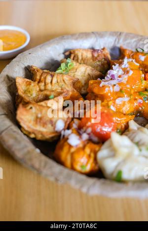 A plate of assorted chicken momos (steamed, fried and chilli sauce ...