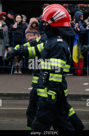 Firefighters in protective gear stand in front of a damaged building ...